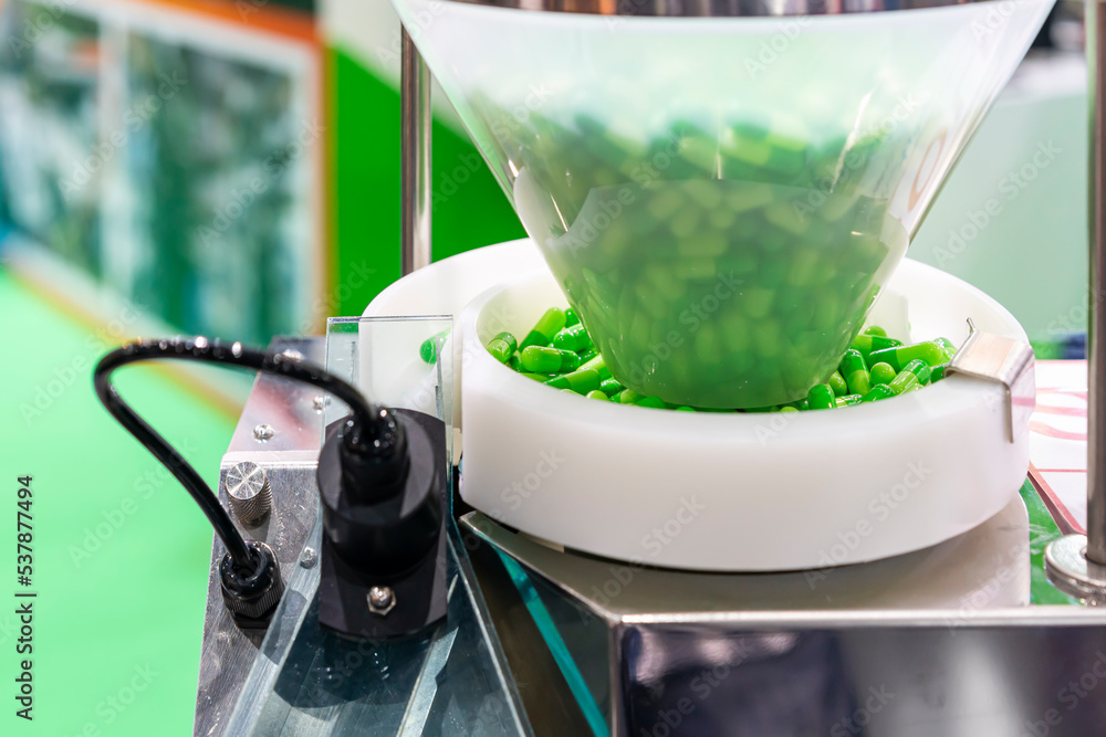 many empty green capsules in plastic hopper for manufacturing process ...