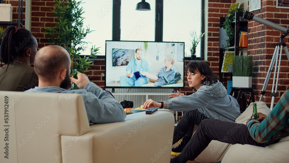 Diverse group of friends looking at action movie on television ...