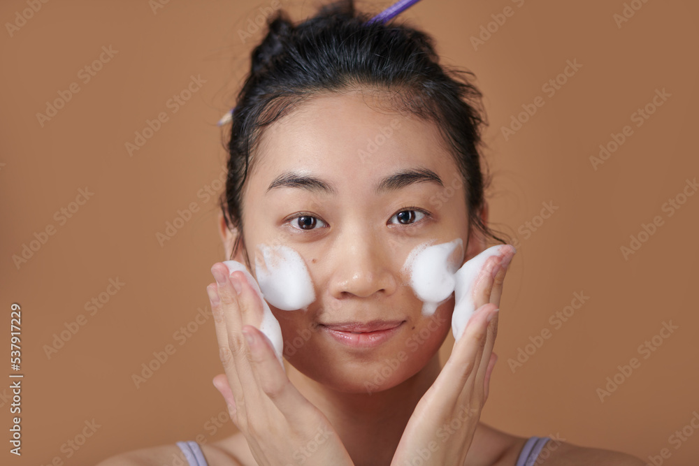 Young beautiful woman washing her face with soap. Stock Photo | Adobe Stock