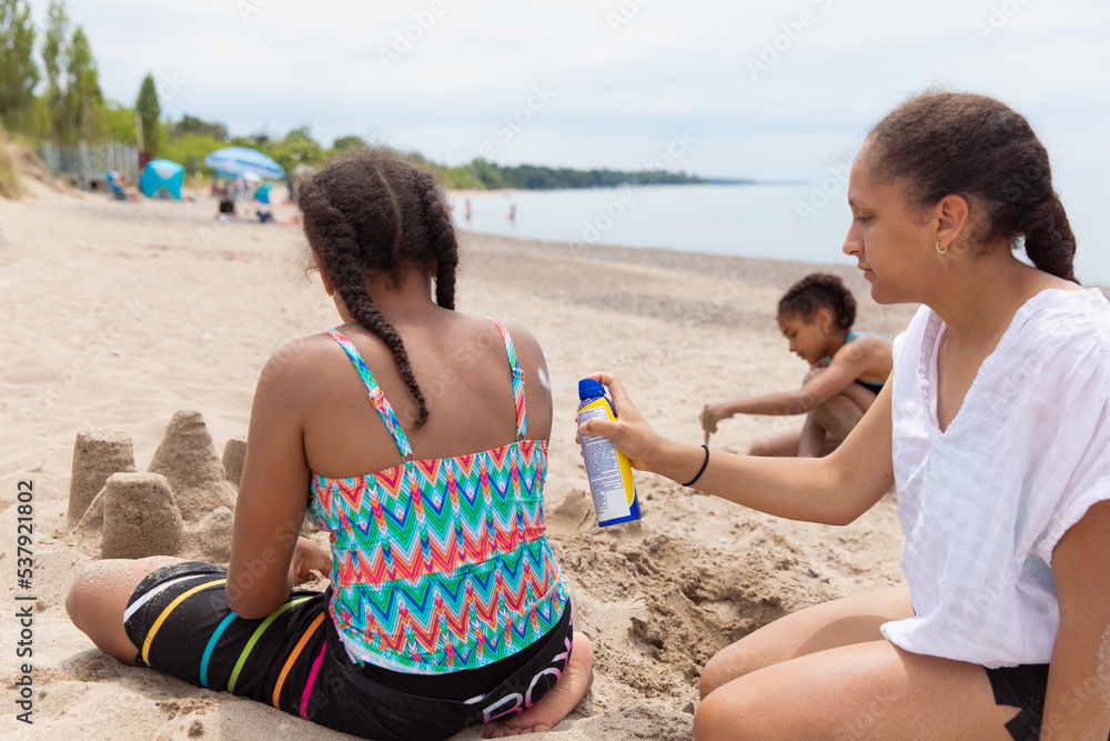 Teen applying sunscreen to her sisters back and shoulder Stock Photo ...