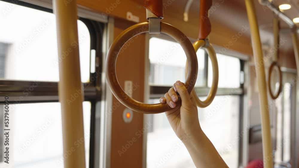 Woman grabs onto round hanging handle on Kagoshima tram; public ...