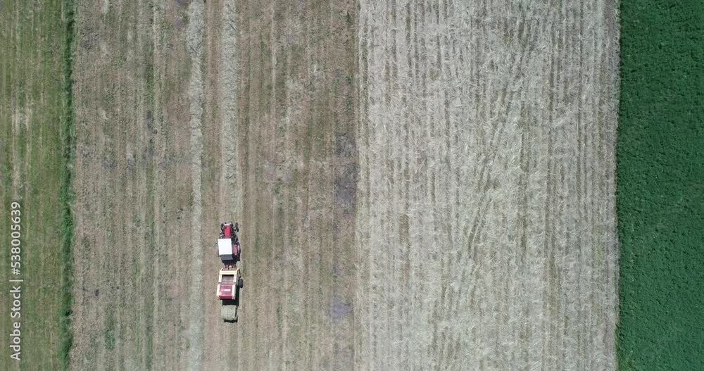 aerial top down of harvesting tractor machine working on the farm land ...