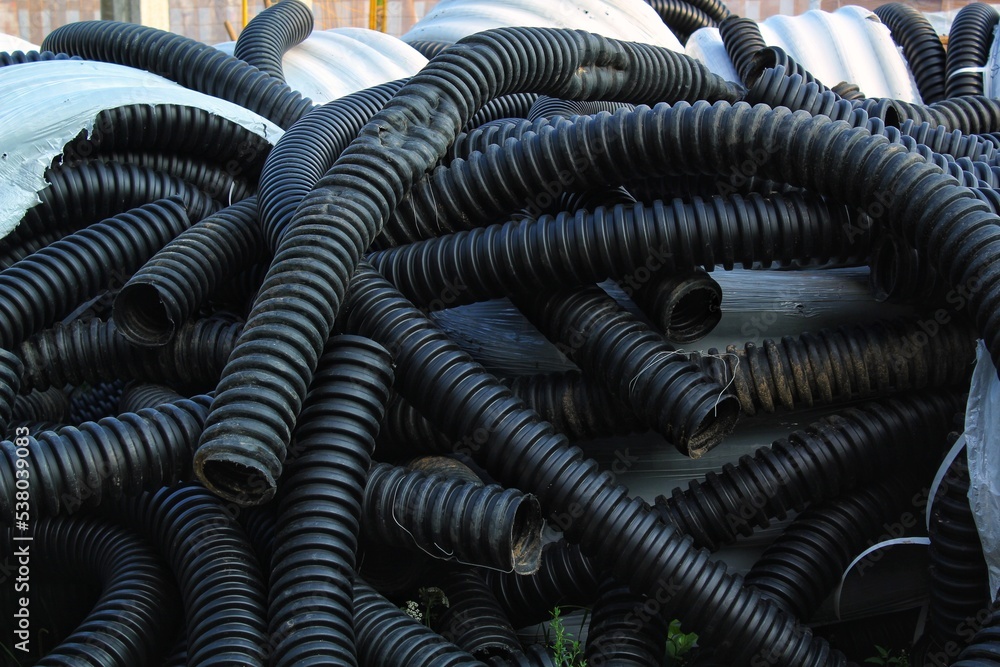 Rolled up pile of twisted, high pressure flexible black rubber pvc ...