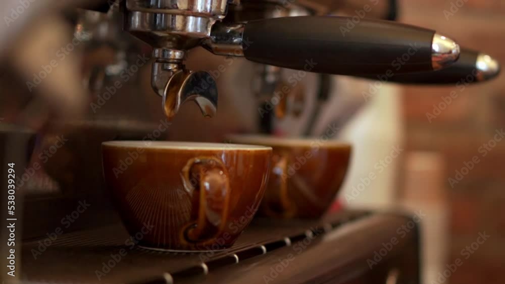 Two brown cups in a professional espresso machine with drops of ...