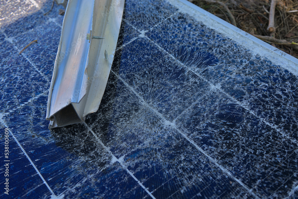 A broken solar panel, a torn panel mount lie on the ground ...