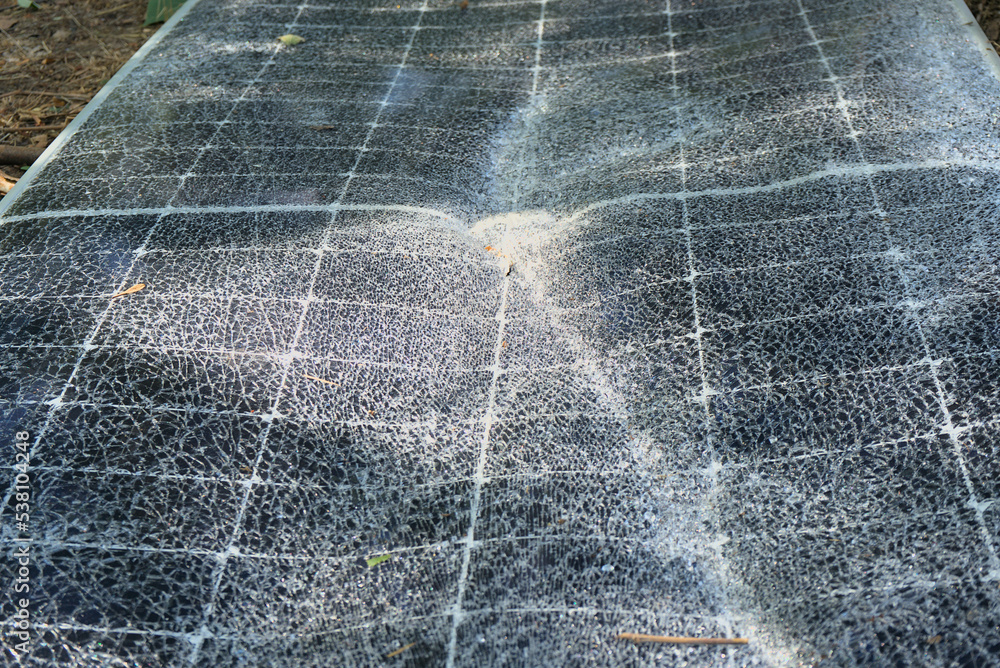 A broken solar panel, a torn panel mount lie on the ground ...