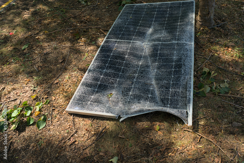 A broken solar panel, a torn panel mount lie on the ground ...