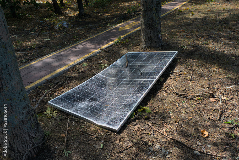 A broken solar panel, a torn panel mount lie on the ground ...