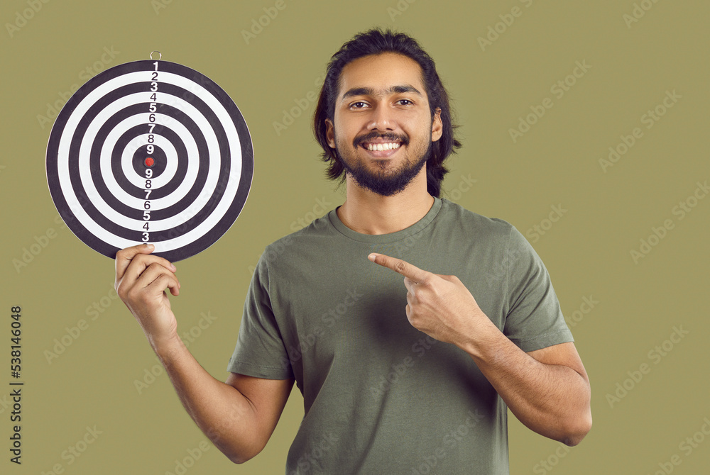 Happy Indian man holding target with concentric circles. Studio shot of ...