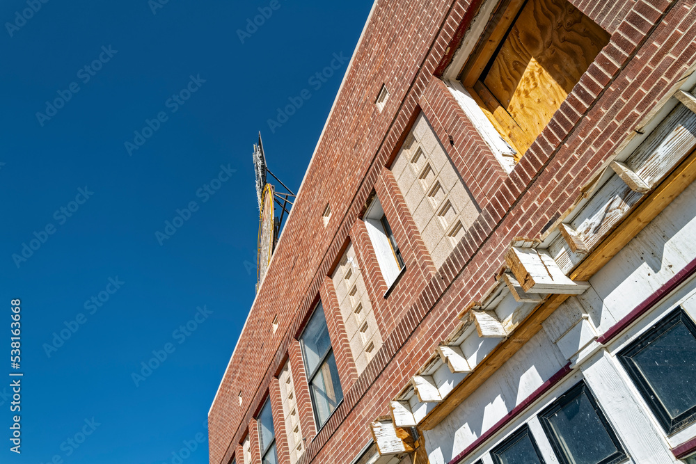 Boarded windows and broken neon sign atop an abandoned brick building ...