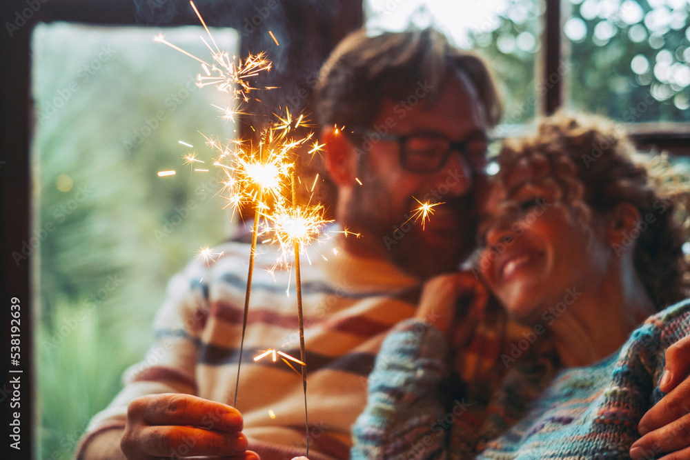 Love and romantic leisure activity with man and woman holding fire sparkler light together ...