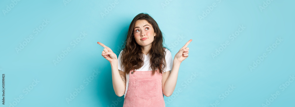 Indecisive beautiful girl thinking, making her choice, pointing ...