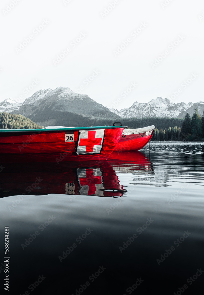Vertical photo of red Lifeboatwith cross on the side in frozen lake in ...