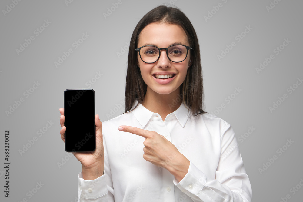 Formally dressed girl in glasses pointing finger at blank screen of ...