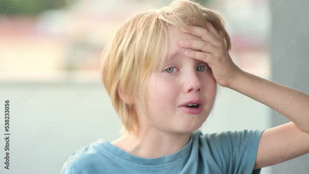 Close-up portrait of crying school-age child. Cute boy with blond hair ...