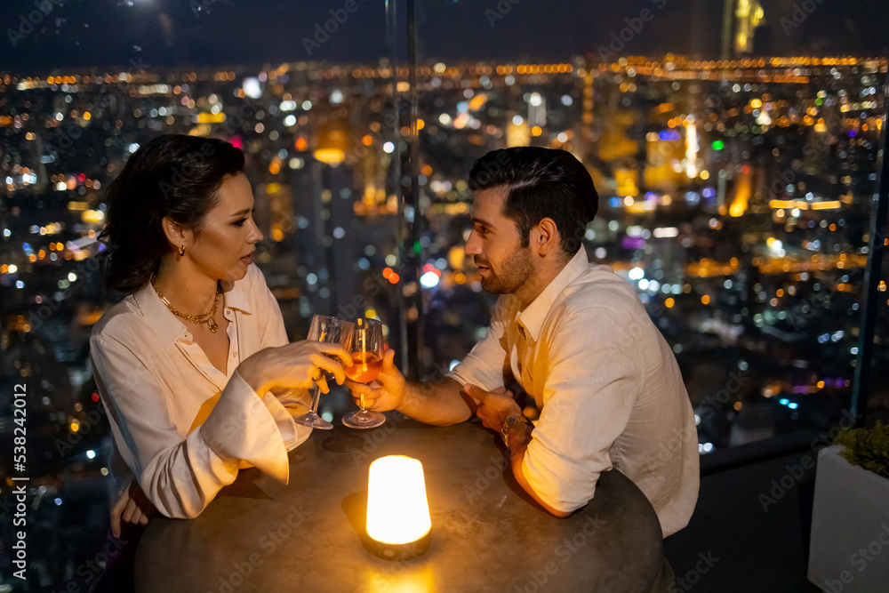 Caucasian couple celebrating holiday event at luxury skyscraper rooftop ...