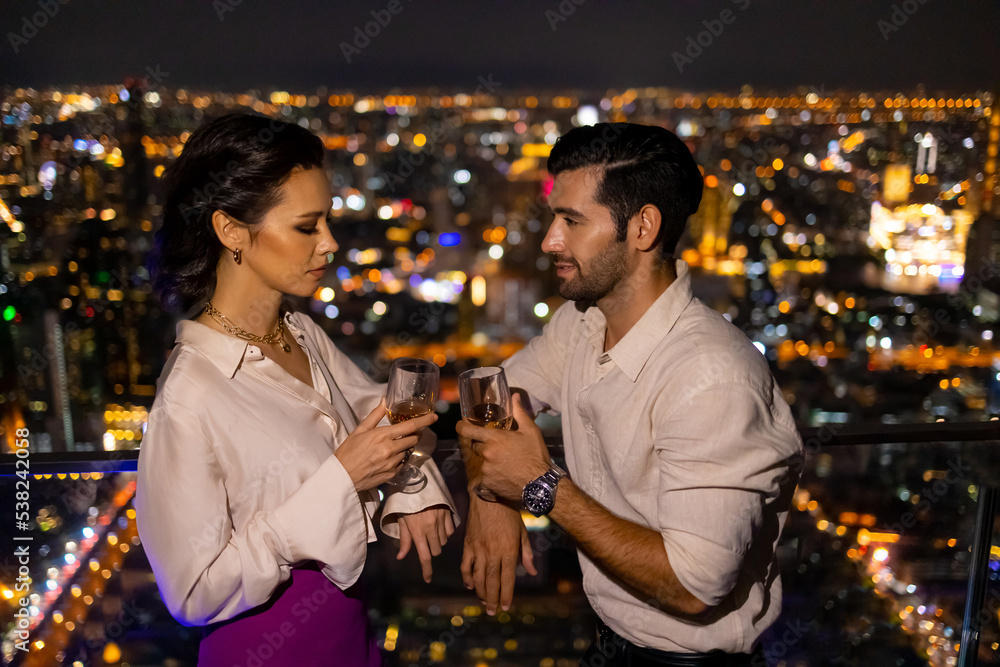 Caucasian couple celebrating holiday event at luxury skyscraper rooftop ...