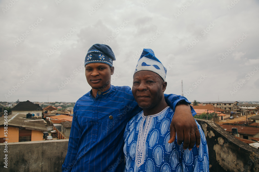 African elderly father side hugging young adult son at the rooftop ...