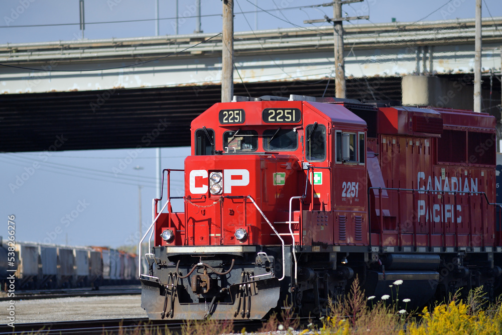 The lead locomotive of a transfer freight train emerges from beneath an ...