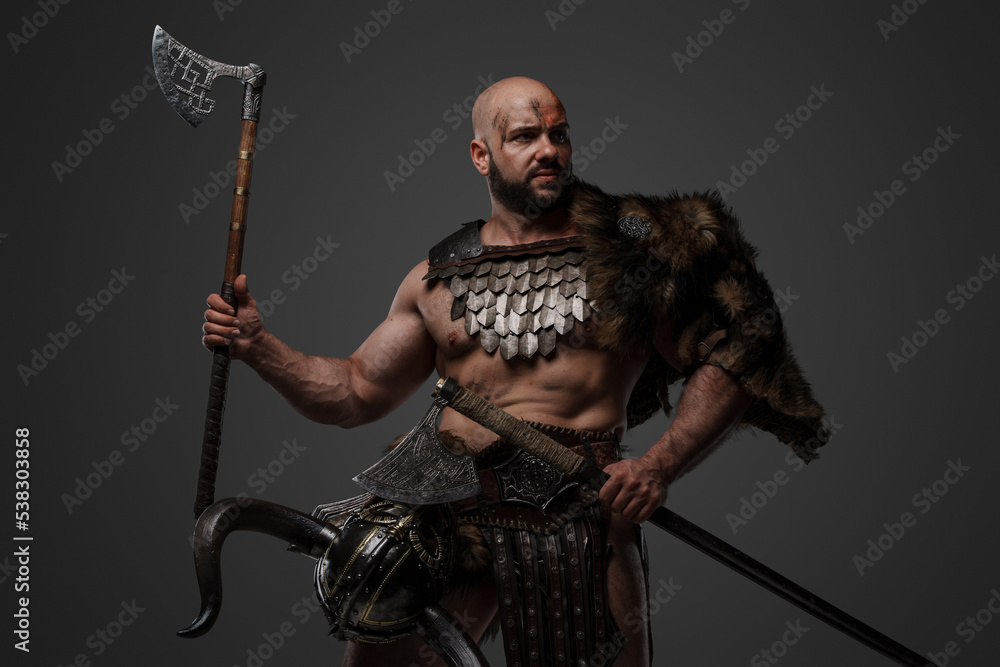 Shot of assaulting viking with muscular build and fur holding two axes ...