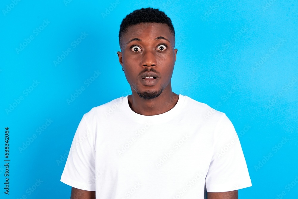 Shocked young handsome man wearing white T-shirt over blue background ...