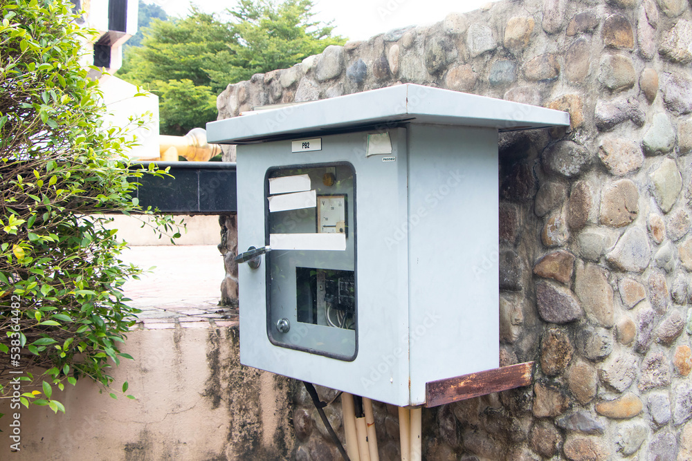 Box electrical is damaged next to gray stone wall temporary ...