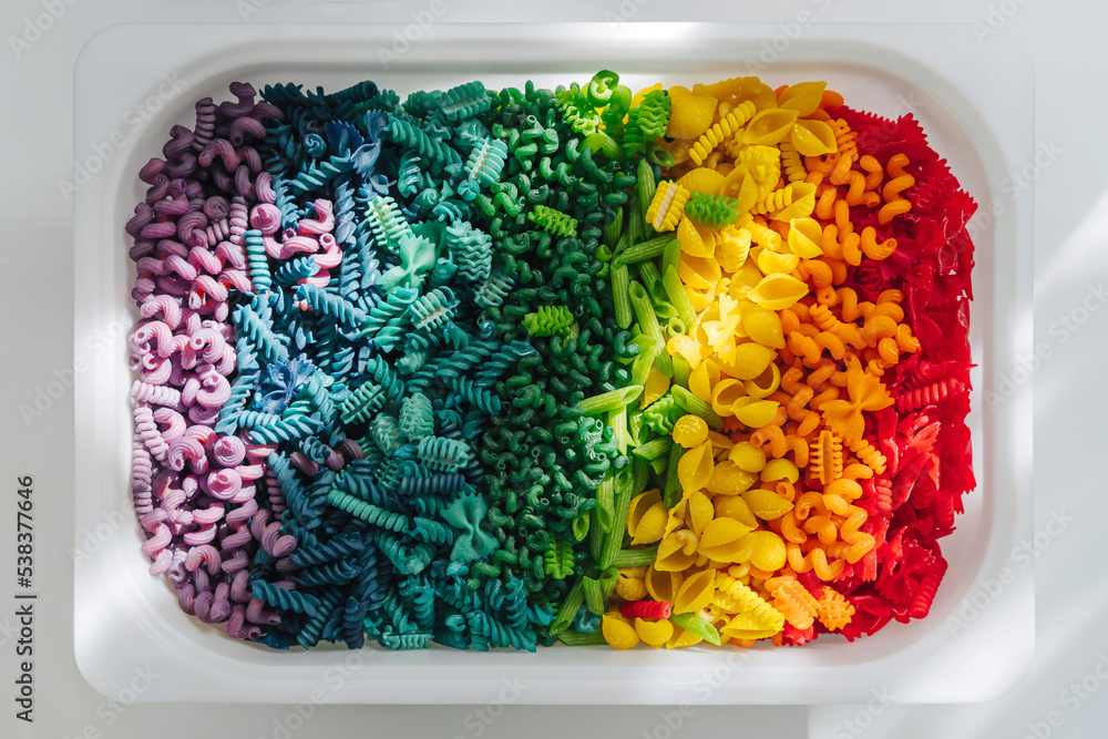 Sensory bin with dried pasta in rainbow colors. Dyed pasta for play and ...