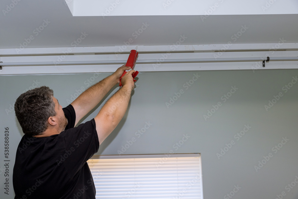 An acrylic sealant is injected into seam between cornice and ceiling ...