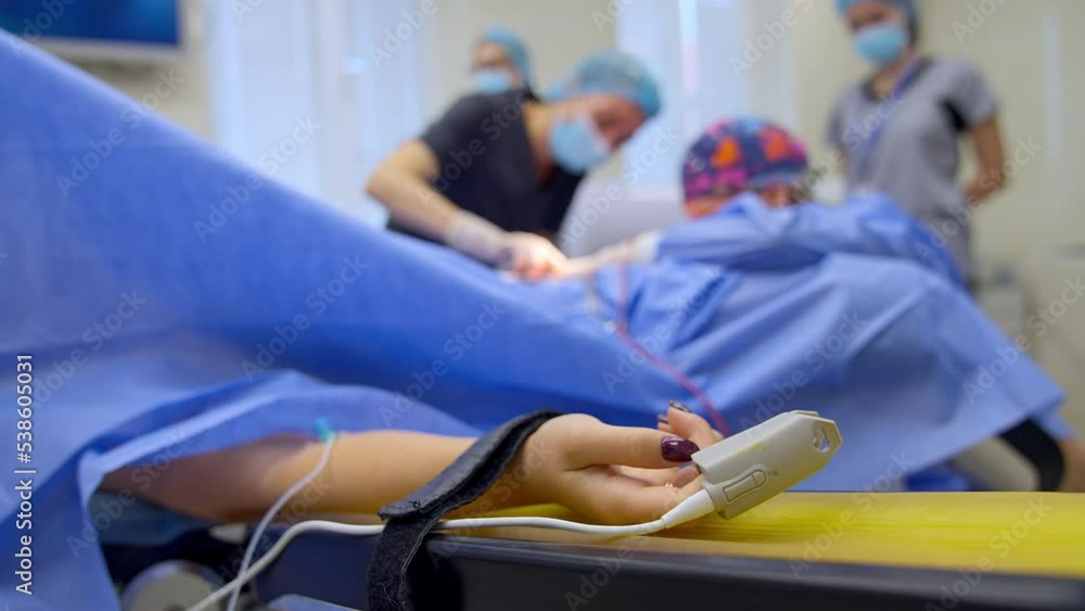 Heart rate sensor on the hand of female patient at surgical operation ...