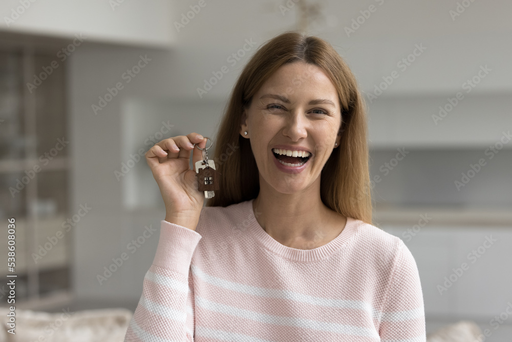 Cheerful young woman poses for camera with keys in hand, symbol of new ...