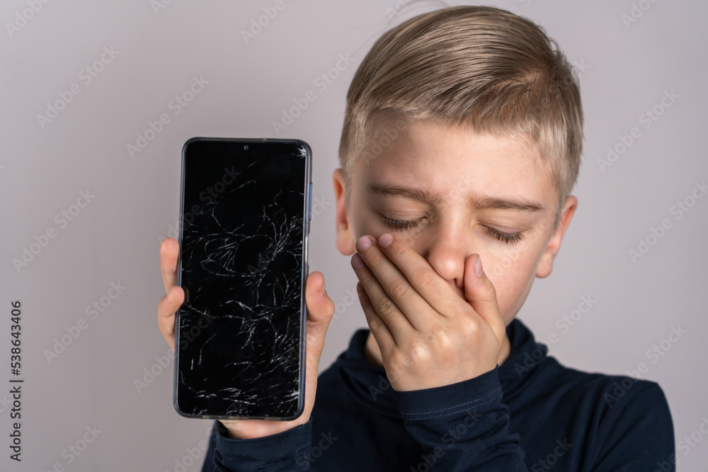 Portrait frustrated kid with broken mobile phone screen, shocked with ...