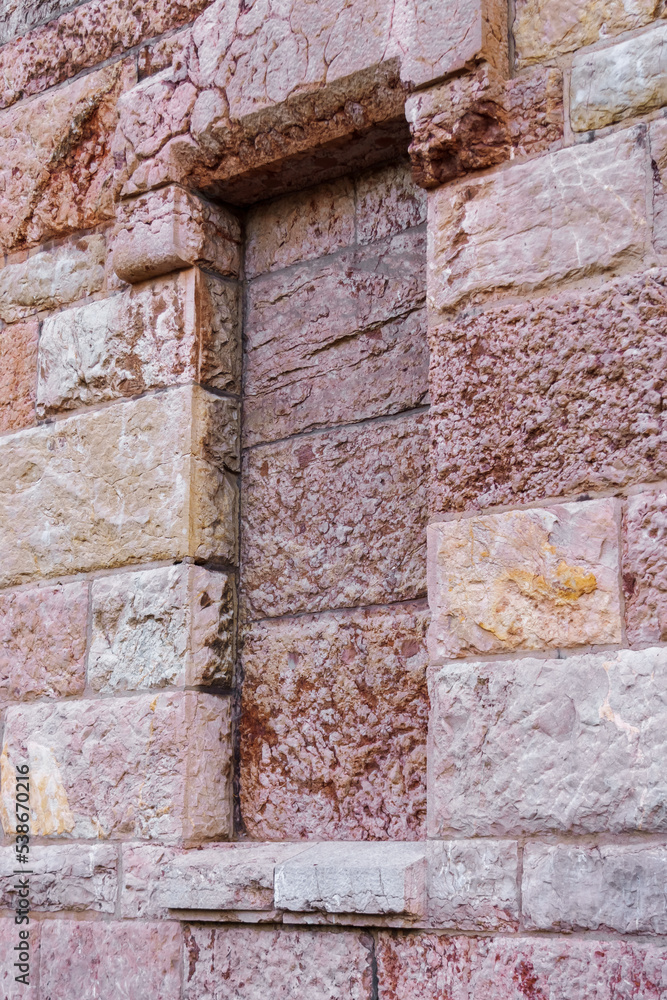 Bricked up window of an old ancient building with uneven stone wall ...