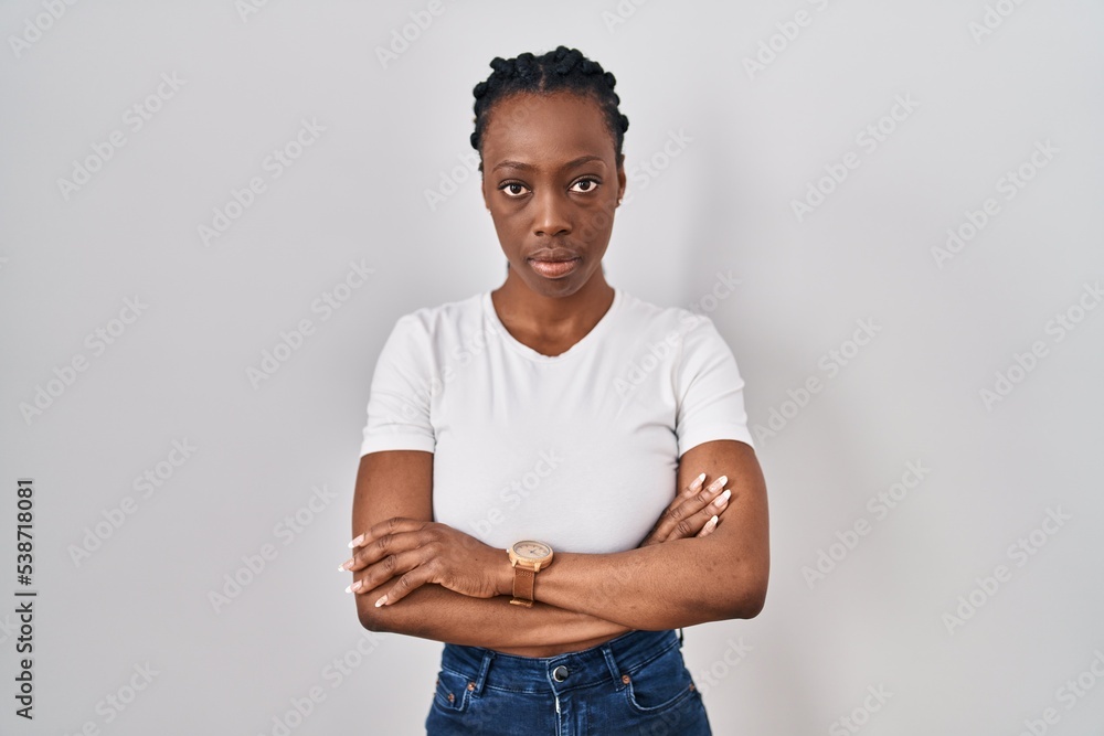 Beautiful black woman standing over isolated background skeptic and ...