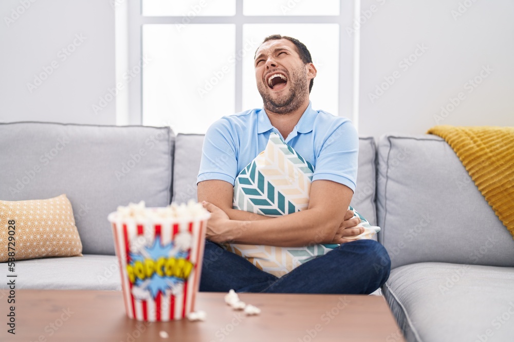 Hispanic man watching tv at home sitting on the sofa angry and mad ...
