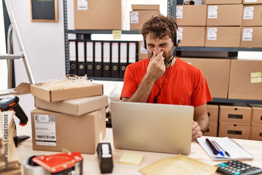 Young hispanic call center agent man working at warehouse smelling ...