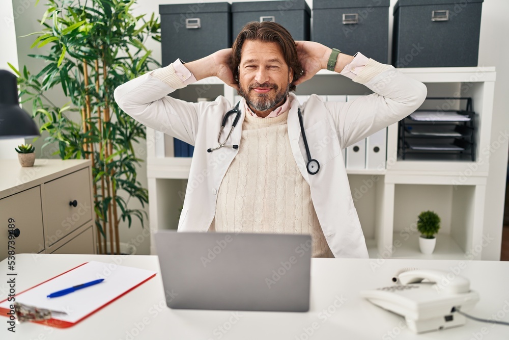 Handsome middle age doctor man working at the clinic relaxing and ...