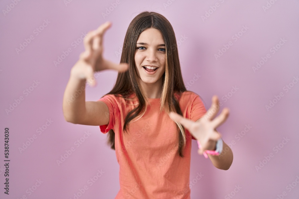Teenager girl standing over pink background shouting frustrated with ...
