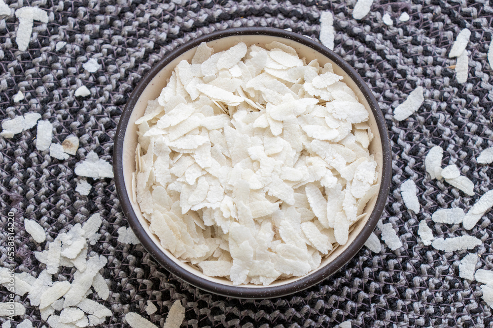 Flattened rice flakes in a carmic bowl, use to make poha recipe in ...