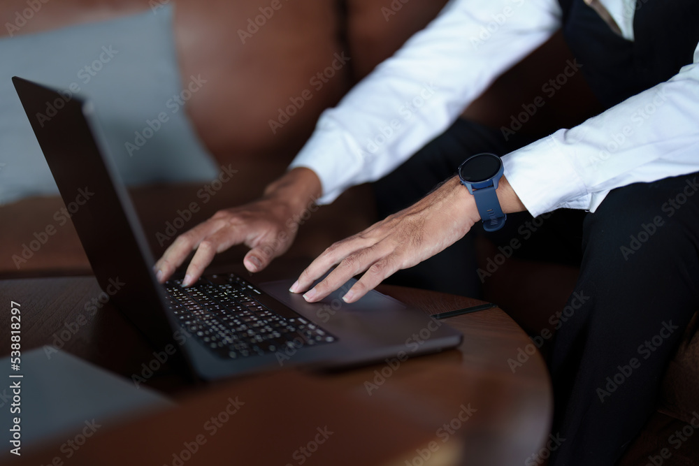 Portrait of a handsome, discreet Asian man sitting on the sofa using a ...