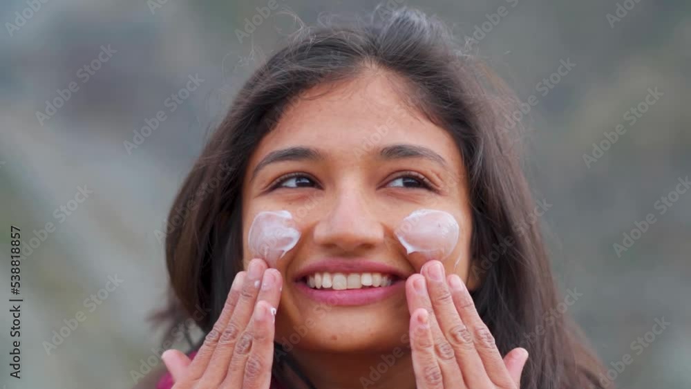Portrait of happy smiling Indian teenager girl applying sunscreen ...