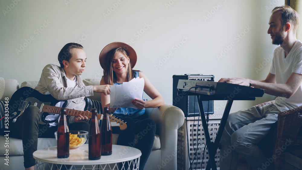 Attractive female vocalist and cheerful male guitarist are reading song ...