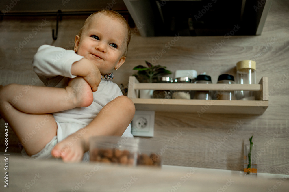 Cute baby girl sitting on kitchen counter at home Stock Photo | Adobe Stock