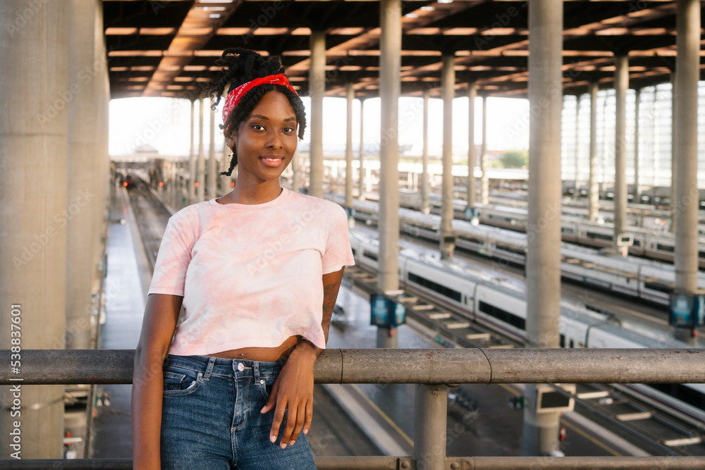 Smiling young woman leaning on railing at railroad station Stock Photo ...