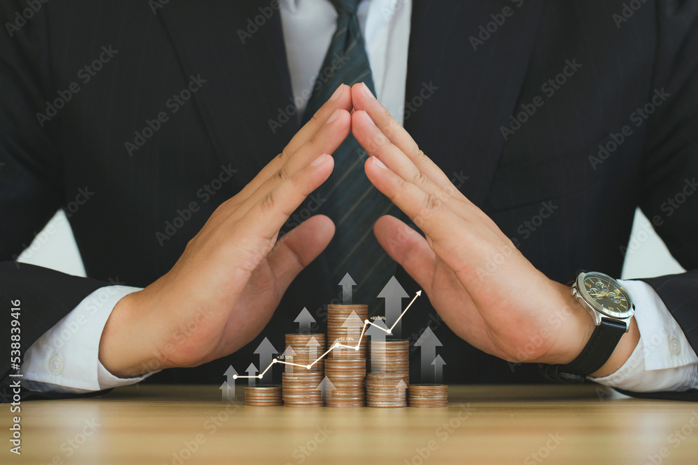 Businessman hands covering a stack of golden coins with stock market ...