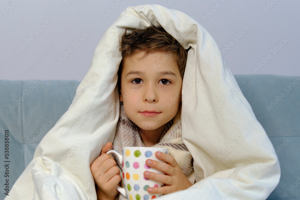 little child boy is sick. A thick scarf is wrapped around her neck ...