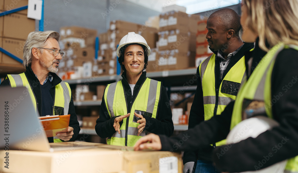 Female warehouse manager having a discussion with her team during a ...