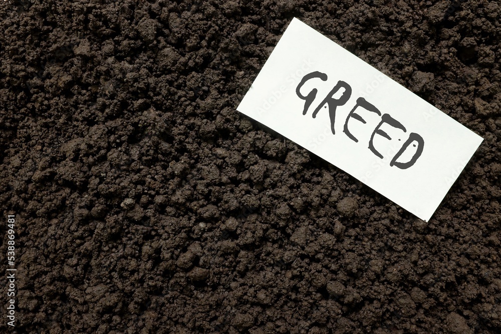 Greed or greedy concept. Paper note with handwritten word on dark soil ...