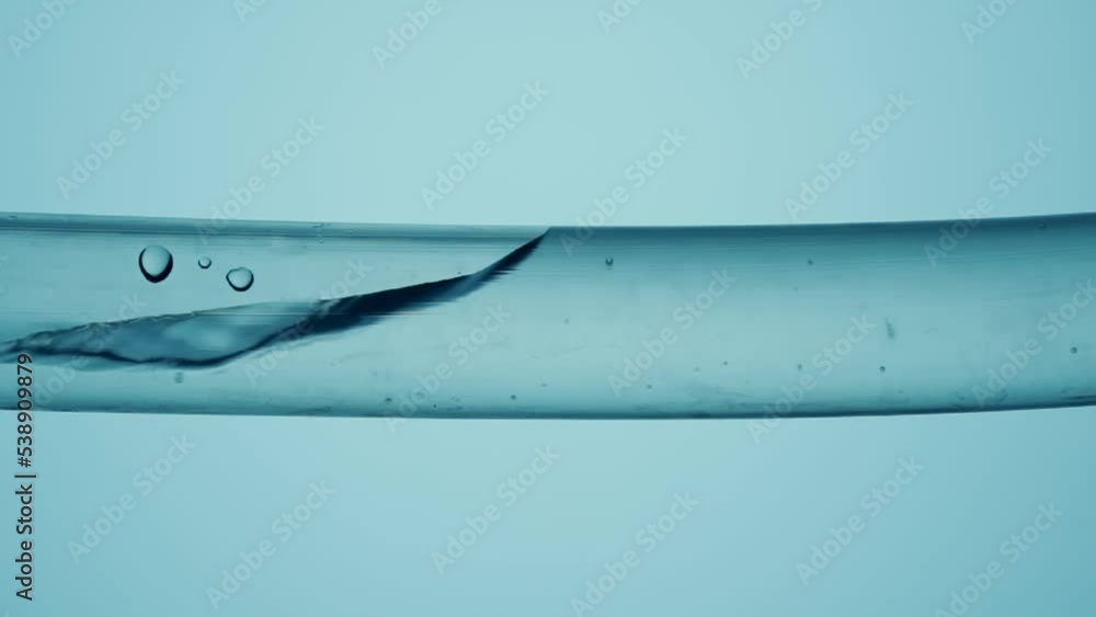 Water flowing in stream inside transparent glass tube on an isolated ...