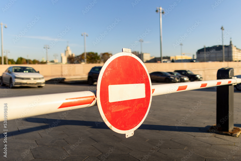 Red round stop sign on an automatic entrance gate on a parking lot ...