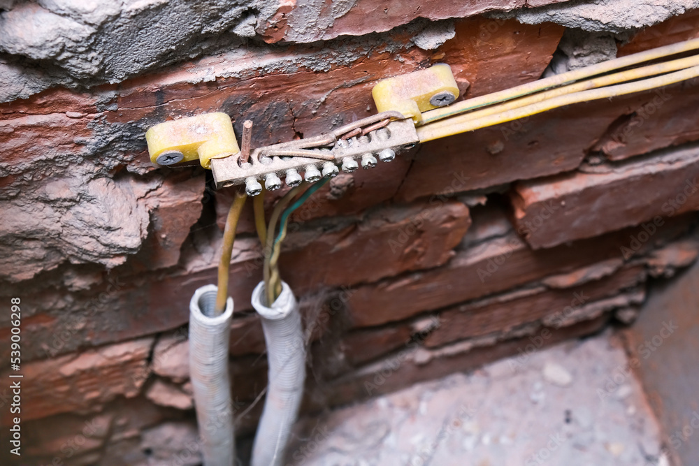 Cables connected to a copper ground bus bar on a brick wall, protection ...
